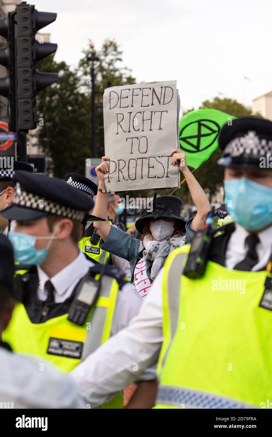 Protester holding up a placard behind police during an Extinction ...