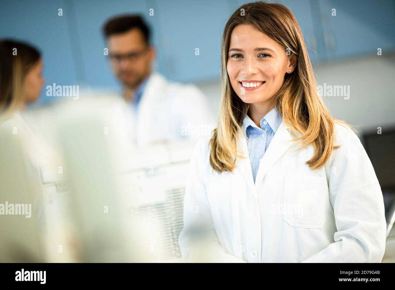 Young female scientist in white lab coat standing in the biomedical lab ...