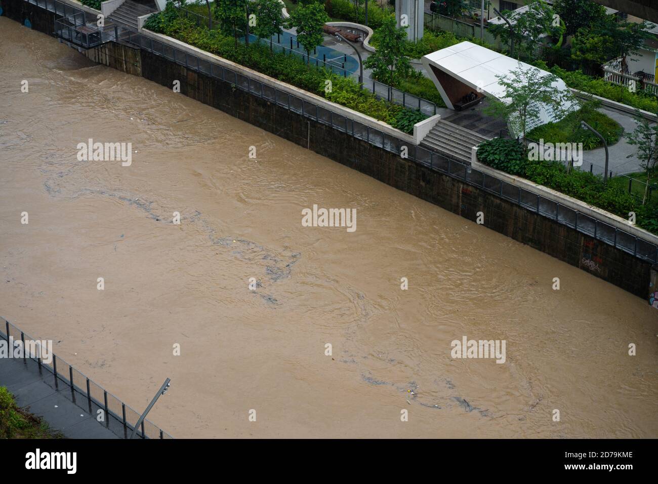 River canal in a big city. Sewage after rain carries garbage along the ...