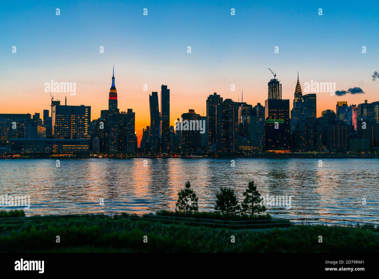 The sun sets to Manhattan skyscraper beyond the East River Stock Photo ...