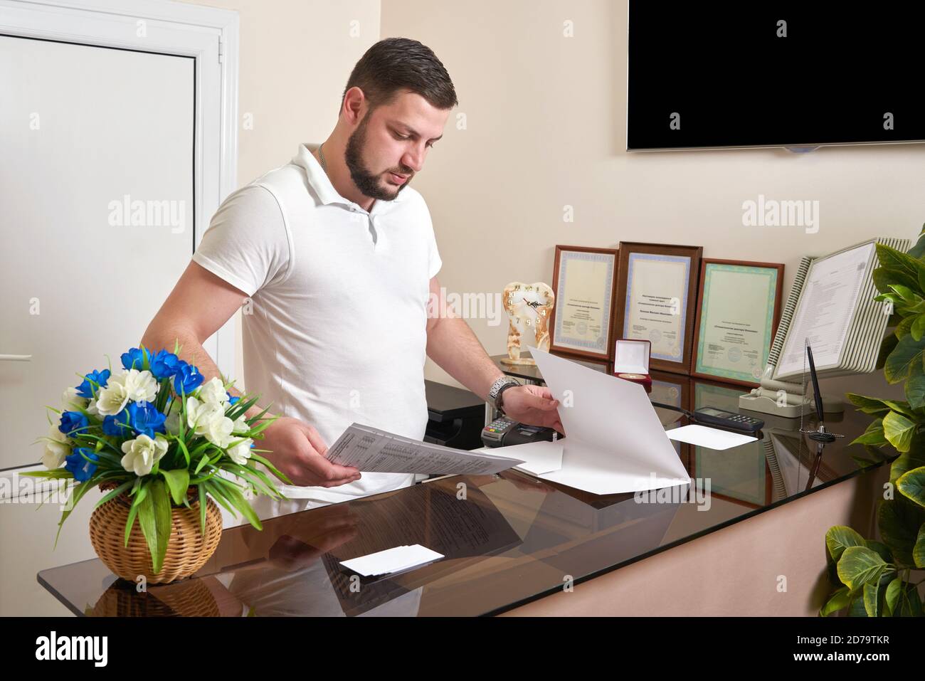 Man at office reception desk working with papers Stock Photo - Alamy