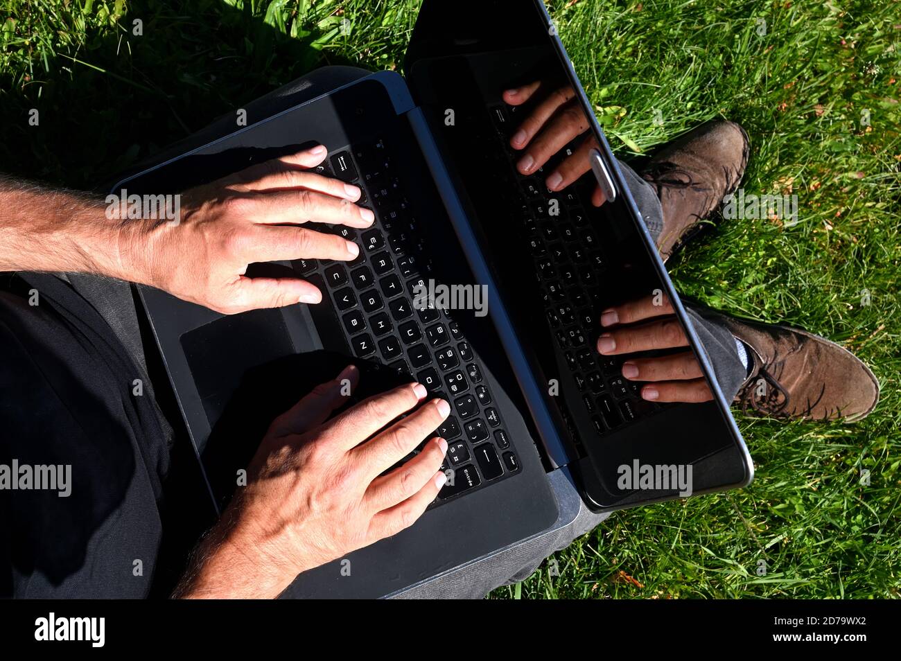 Man sitting in a field working on computer Stock Photo - Alamy