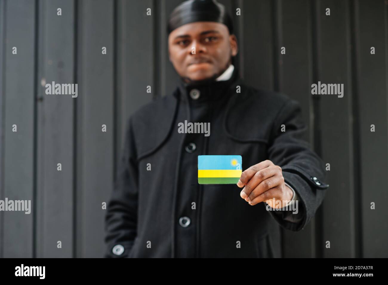 African man wear black durag hold Rwanda flag at hand isolated dark ...