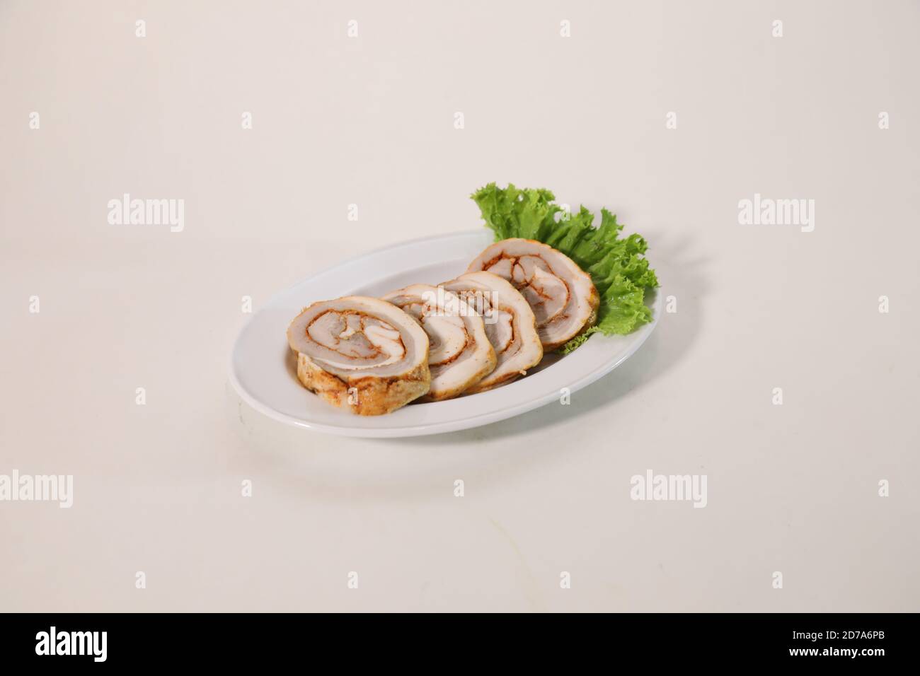 Closeup of delicious pork roulette slices in a plate isolated on a gray ...
