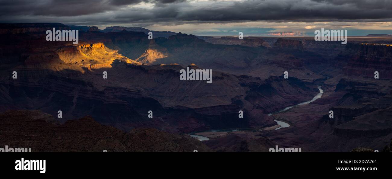 The Colorado River passing below golden cliffs of the Grand Canyon at ...