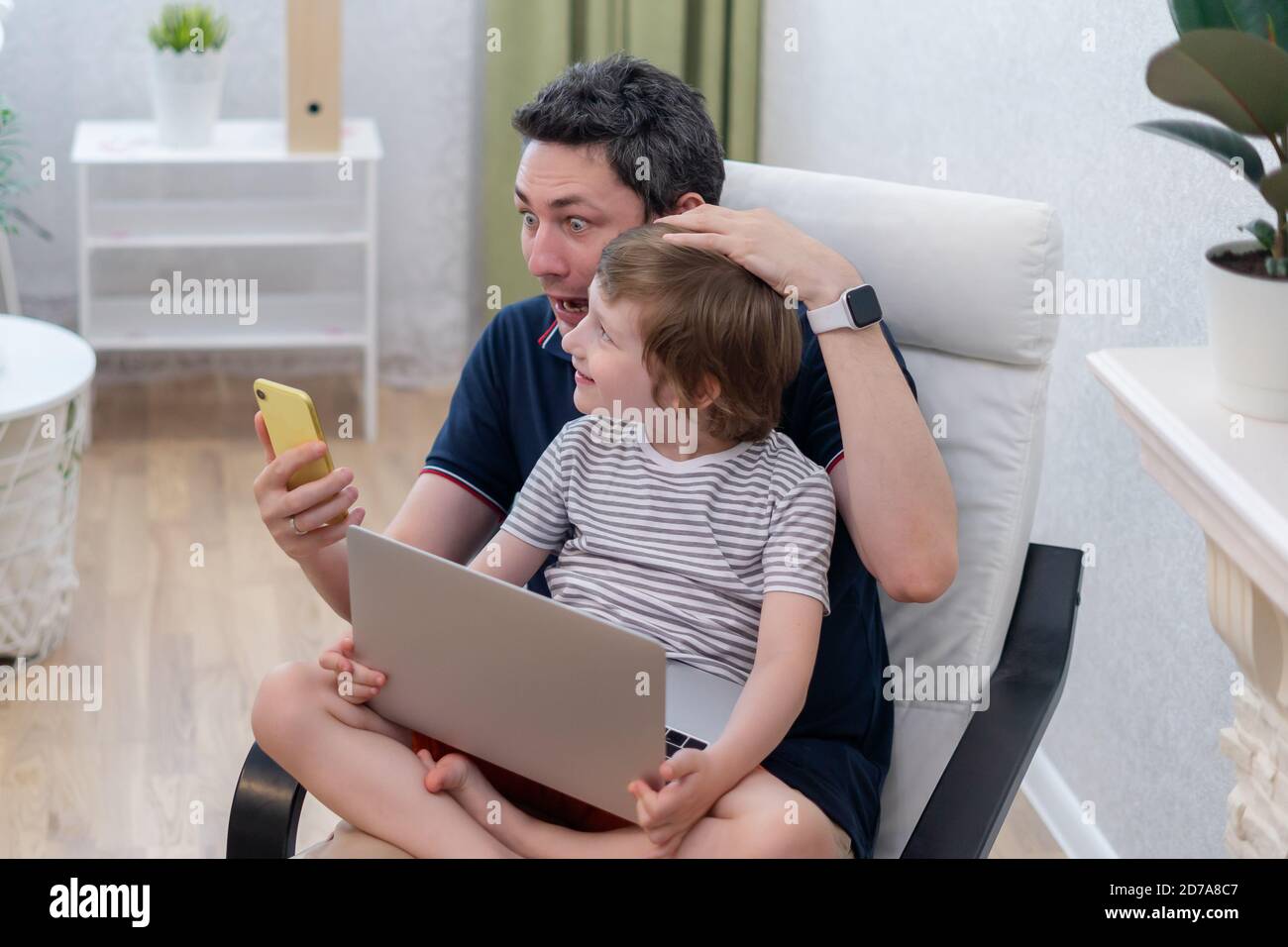 Surprised young man sit on computer using laptop relax with preschooler ...