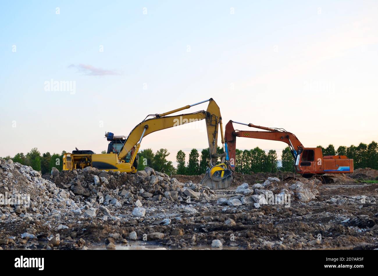 Two excavators at a construction site. Excavator with crusher bucket ...