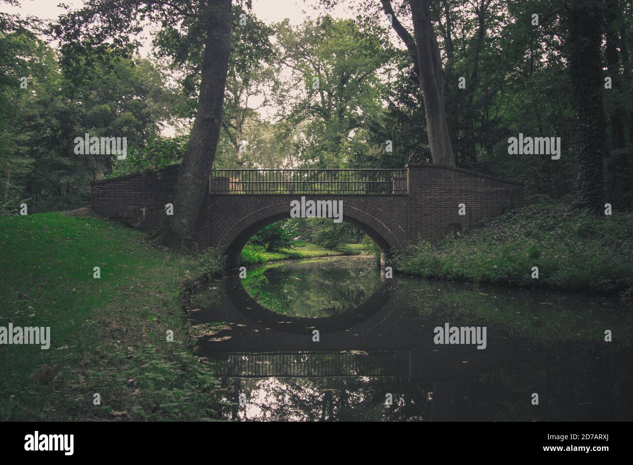 Small stone arch bridge over reflective pond water in Burger park in ...