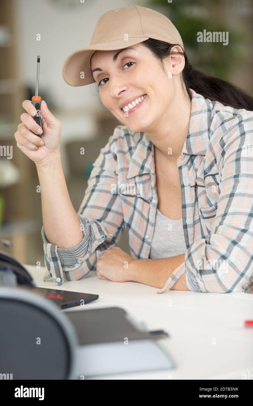 capable woman sat at a desk holding a screwdriver Stock Photo - Alamy