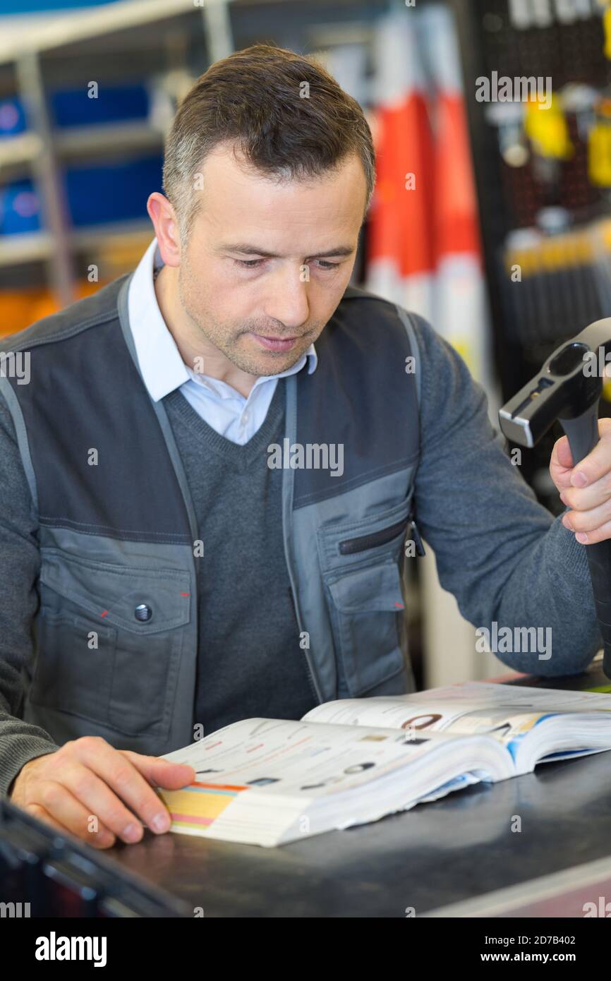 workman holding hammer reading book Stock Photo - Alamy
