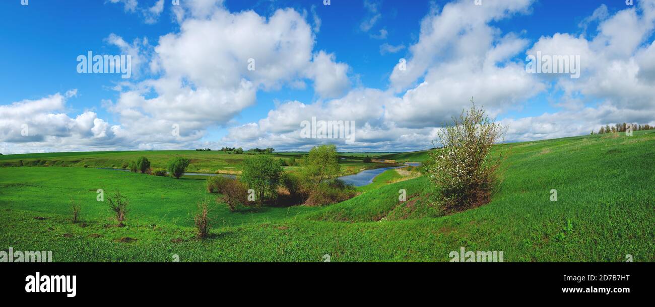 Sunny spring landscape with river and beautiful clouds in blue sky ...