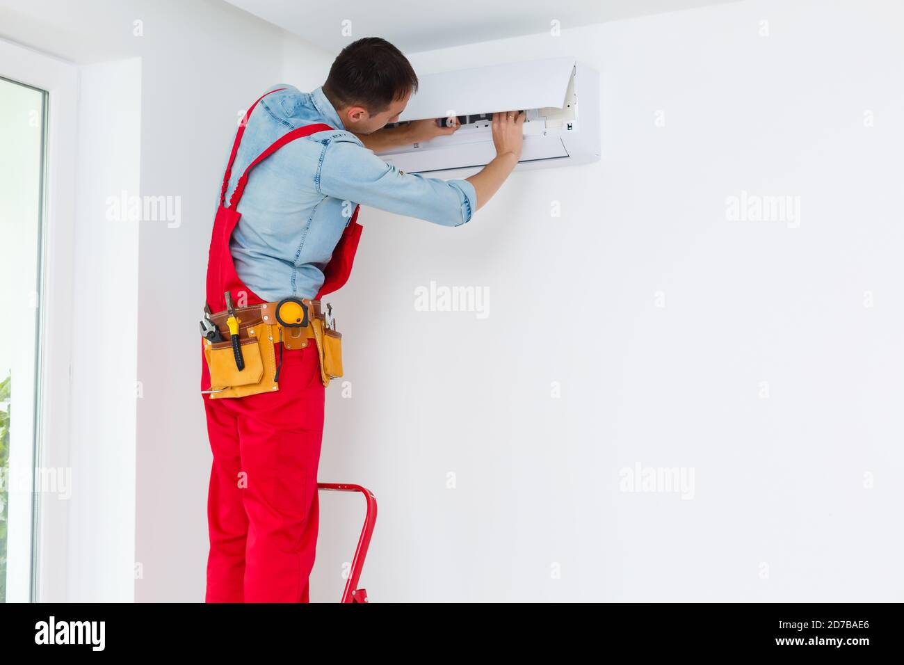Young Man Repairing Air Conditioner Standing On Stepladder Stock Photo ...