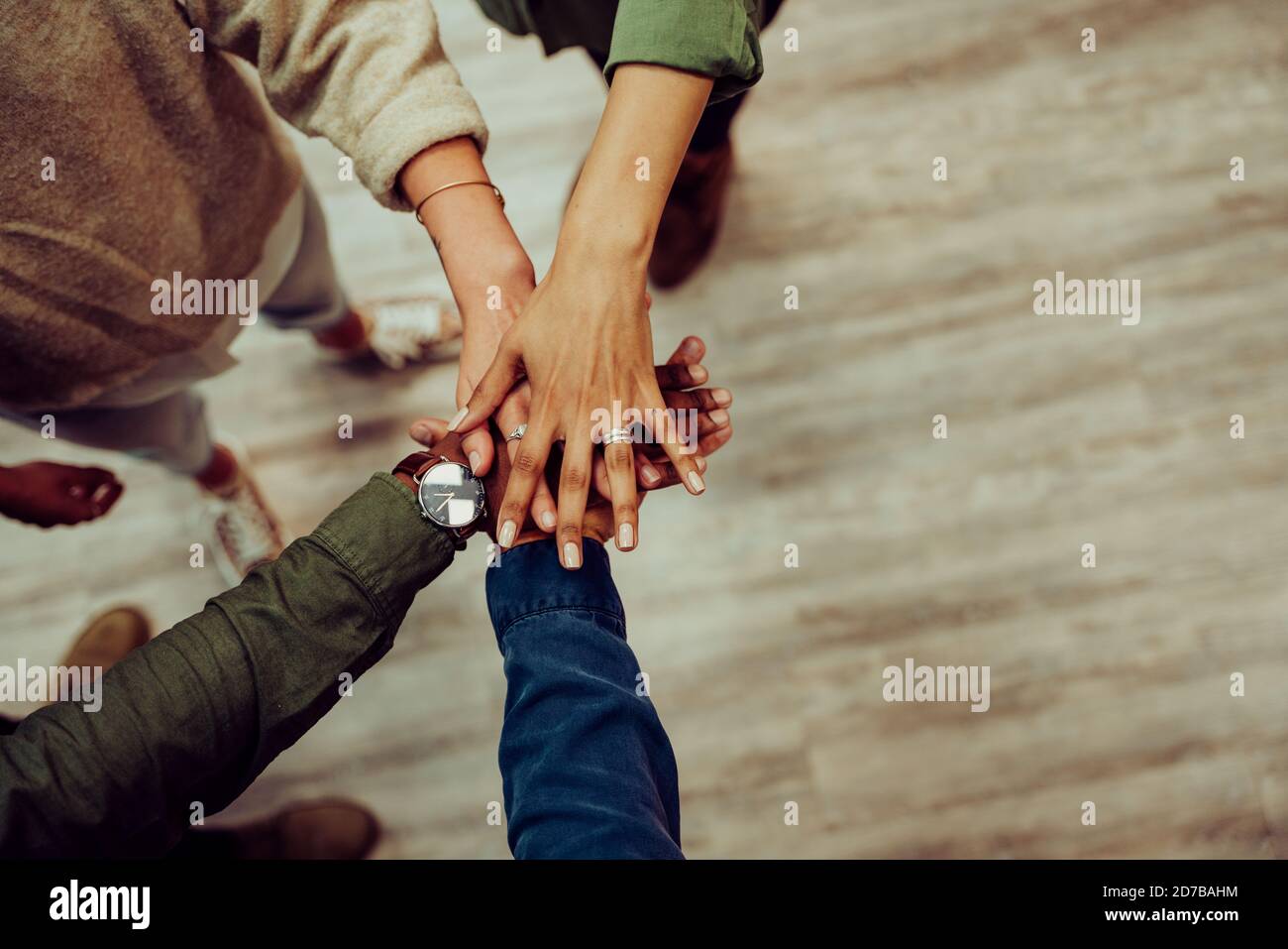 Diverse group of people gathering to stack hands showing unity and ...