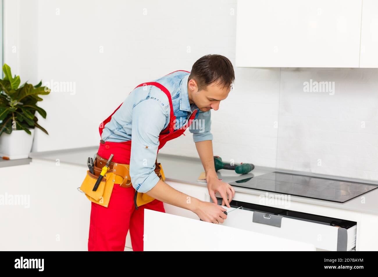 Handyman fixing kitchen's cabinet with screwdriver Stock Photo - Alamy