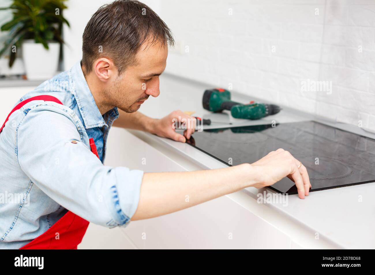 thoughtful adult repairman repairing electric stove at kitchen Stock ...