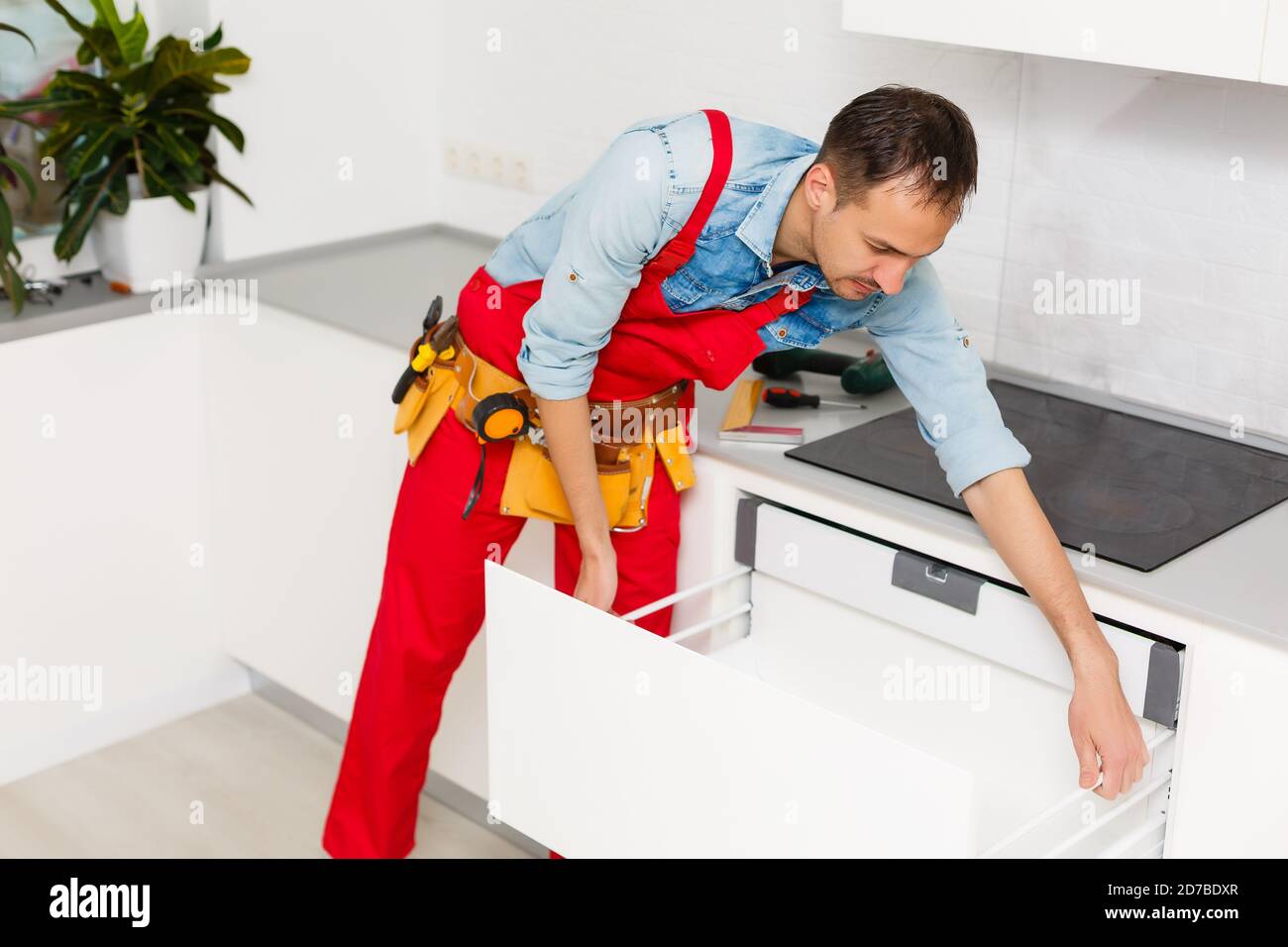Handyman fixing kitchen's cabinet with screwdriver Stock Photo - Alamy