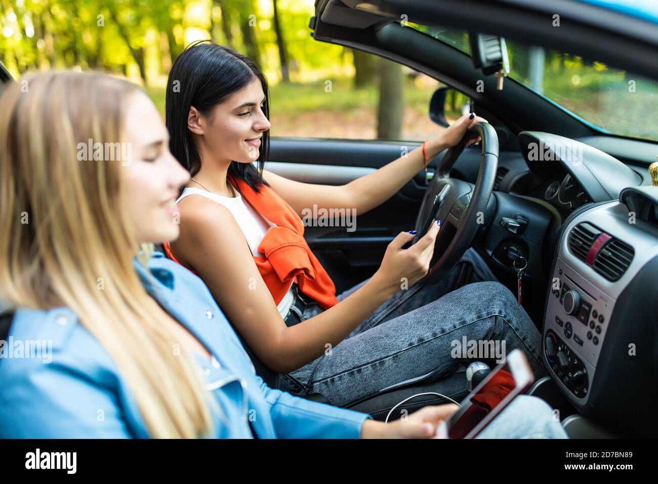 Two girls use phone watch something in social network while driving the ...