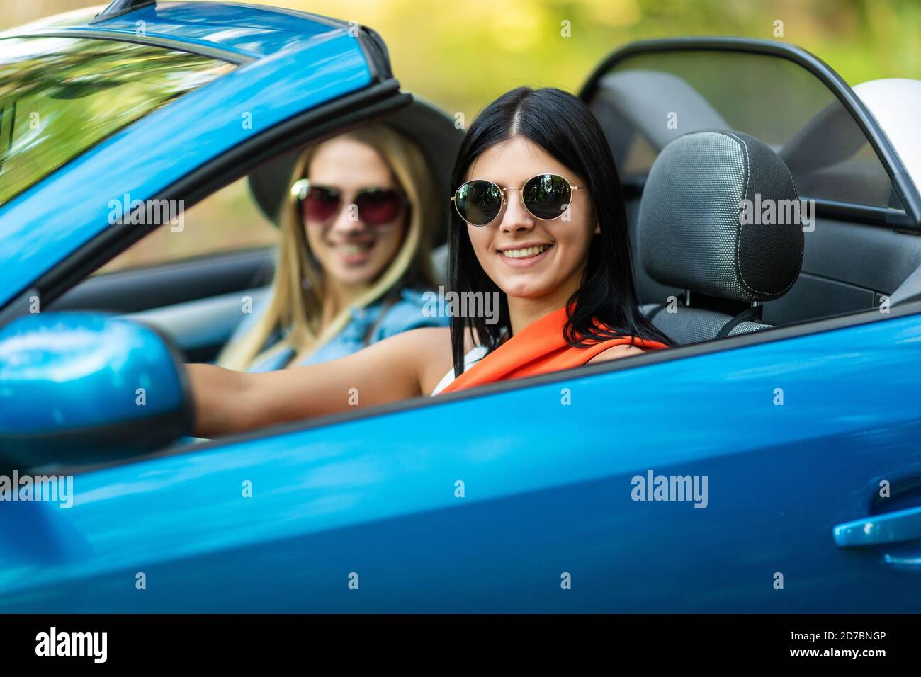 Two happy friends in white cabriolet car driving everywhere and looking ...