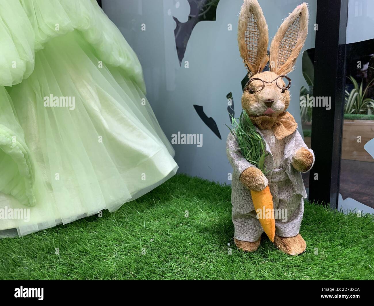 Brown rabbit toy standing on a grassy floor holding a carrot Stock ...