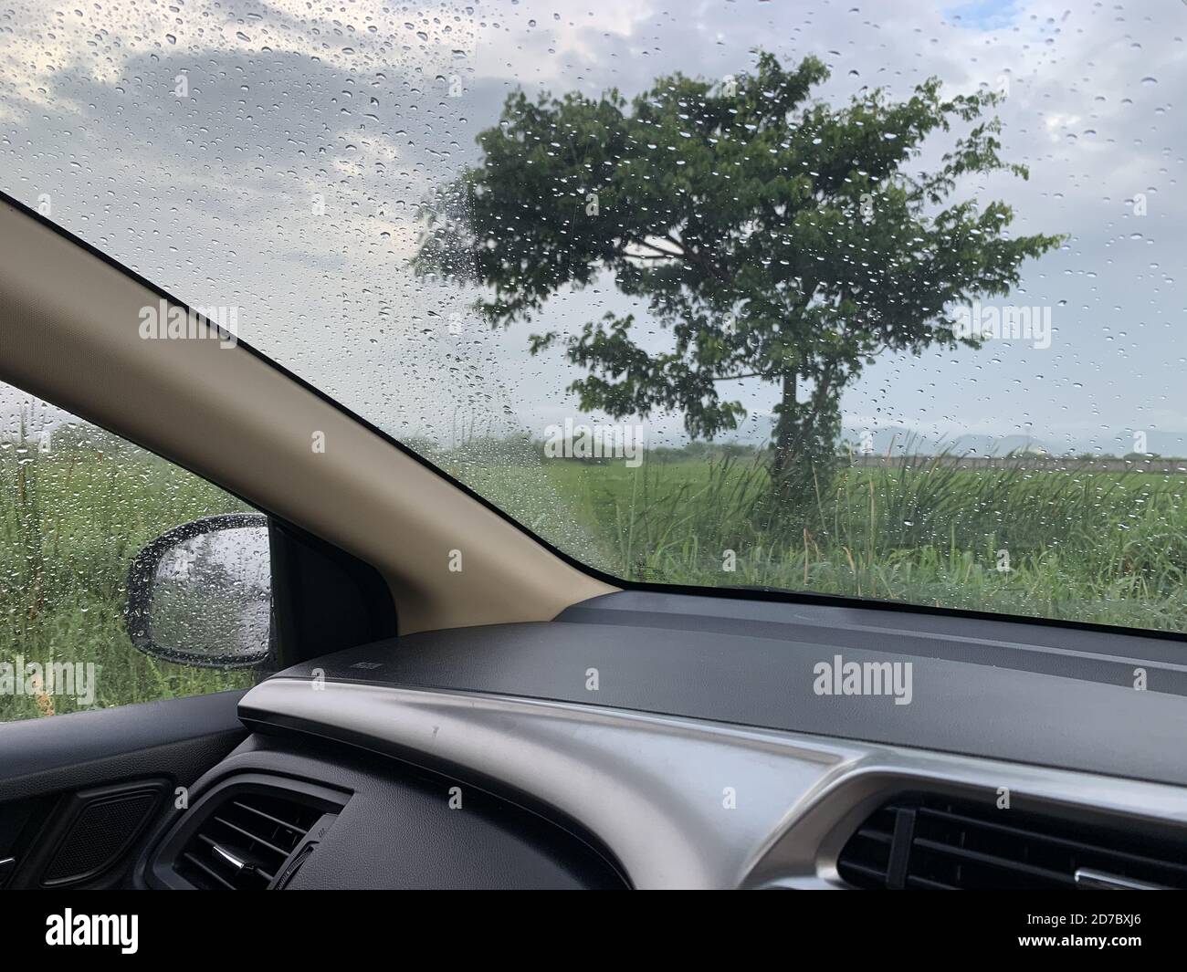 Interior of a car parked in a field under a cloudy sky during the rain ...