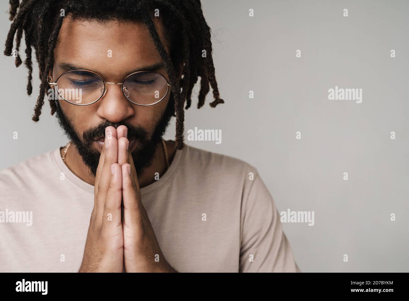 Image of serious praying african guy isolated over grey wall background ...