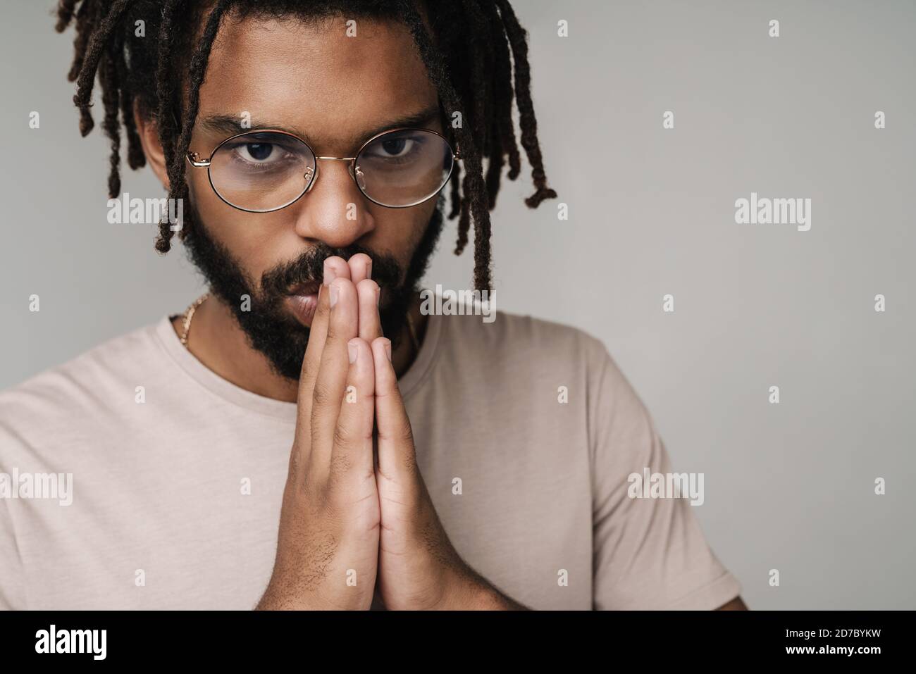 Photo of handsome serious praying african guy isolated over grey wall ...