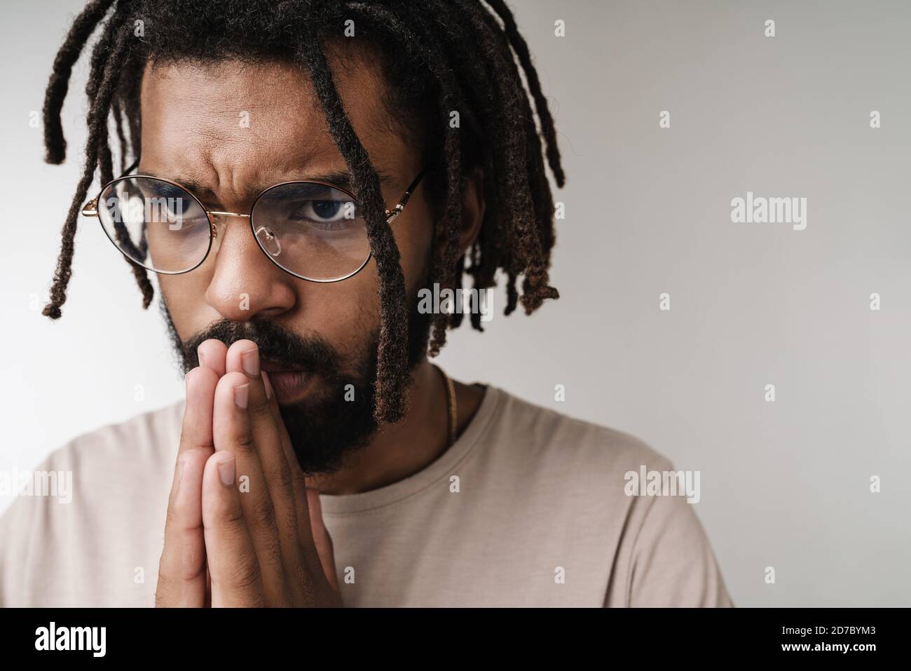 Photo of handsome serious praying african guy isolated over grey wall ...