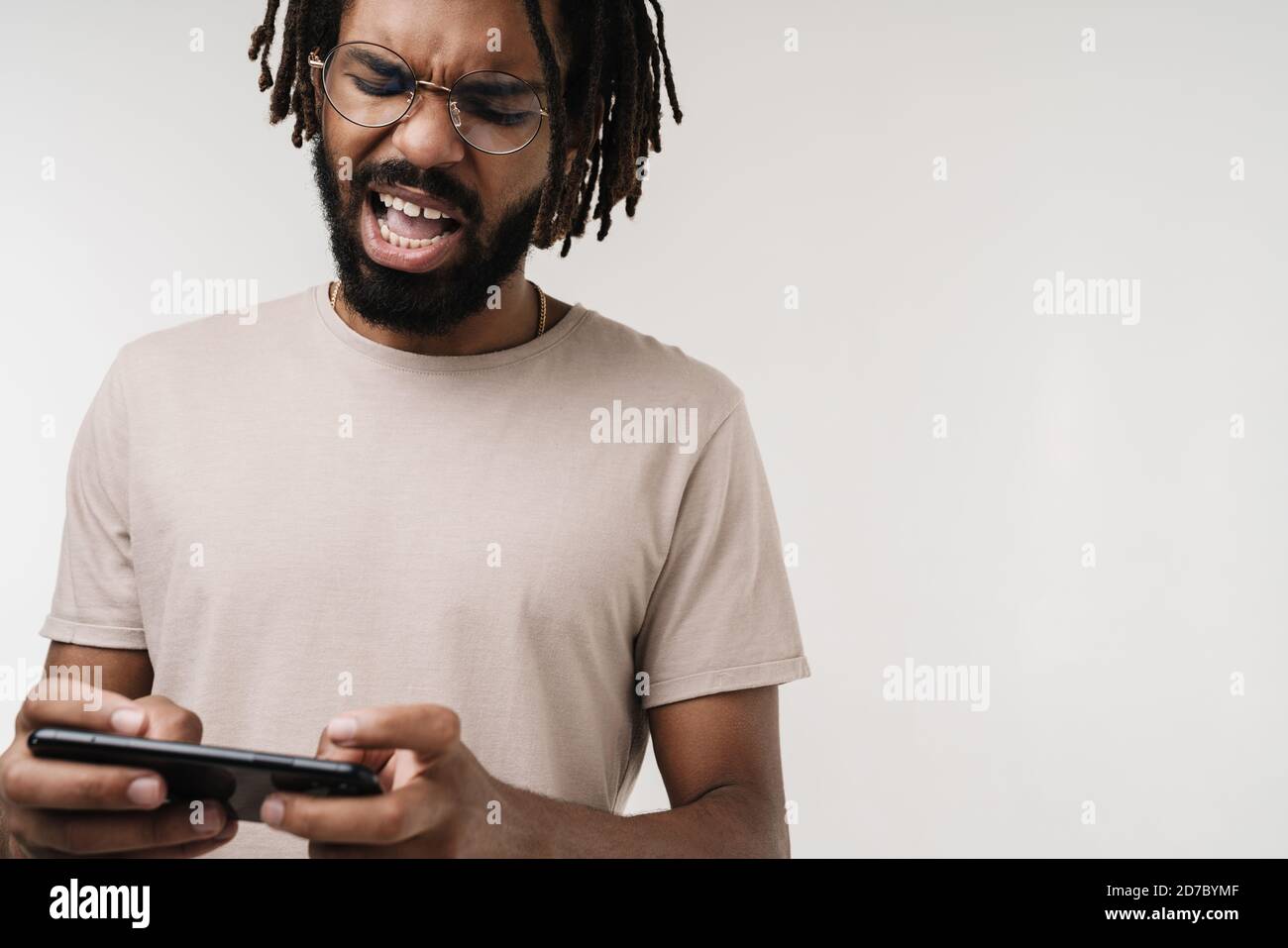 Photo of nervous emotional african guy playing games by mobile phone ...