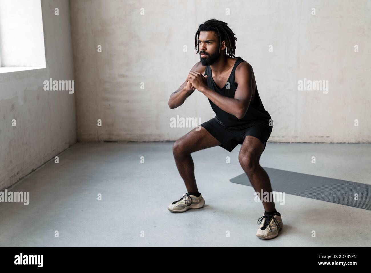 Image of young african american sportsman doing exercise while working ...