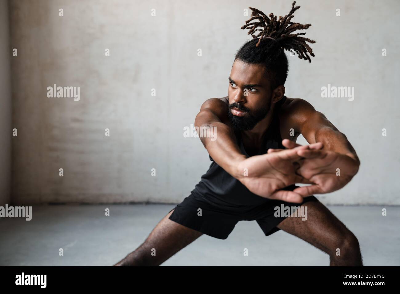 Image of young african american sportsman doing exercise while working ...