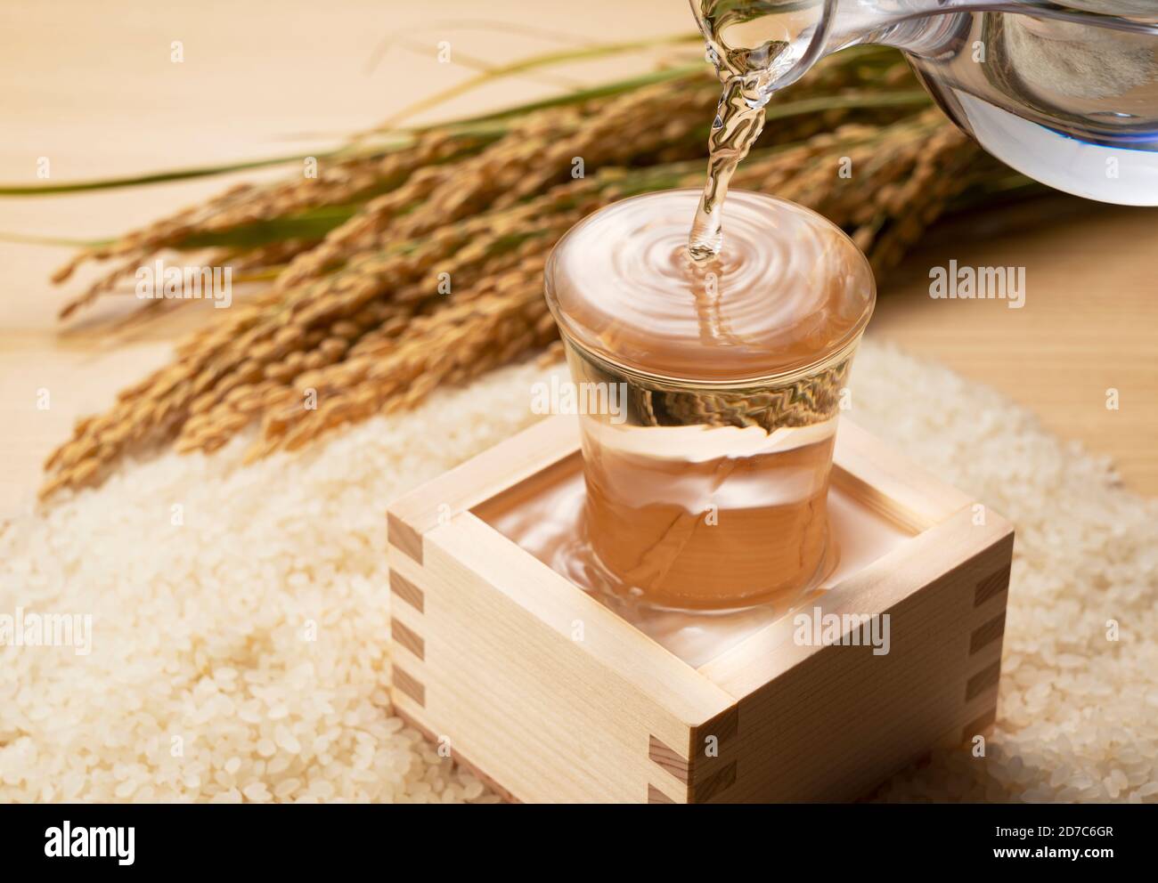 Pour the sake into a sake glass. Rice and ears of rice in the ...