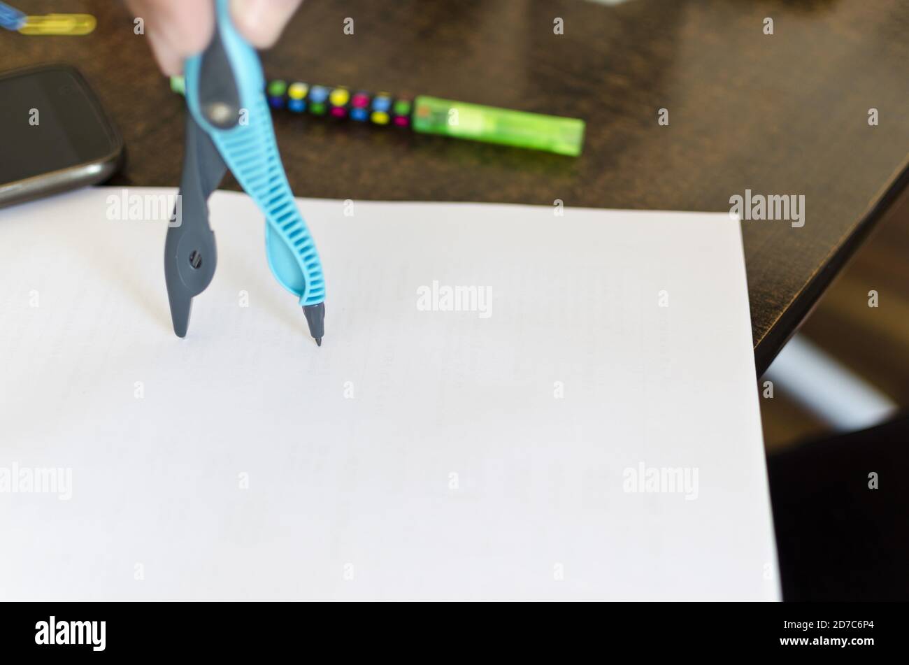 Closeup of blue and grey calipers used on a piece of white paper on a ...