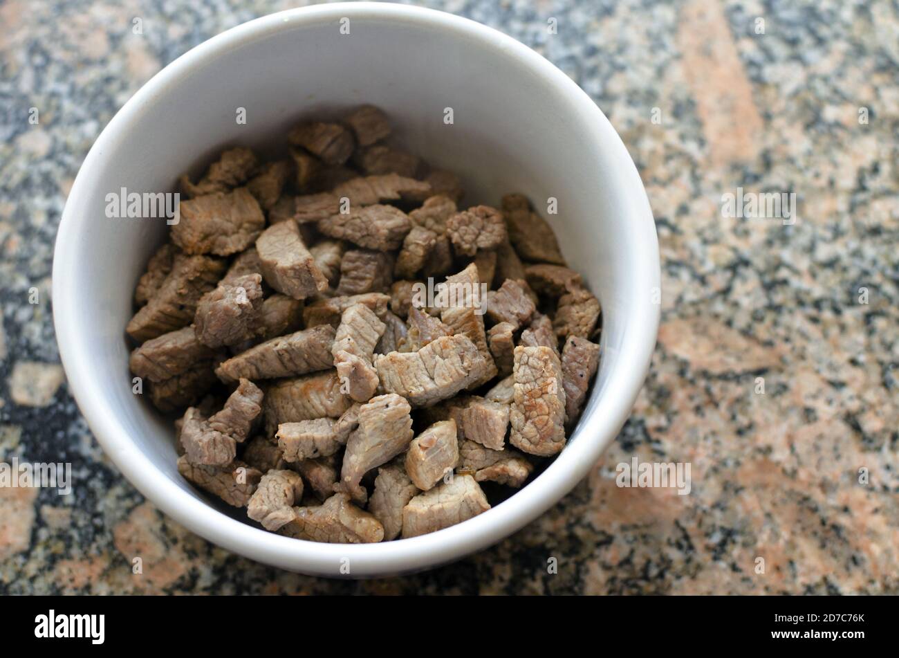 Top view closeup of cooked and cut beef slices in a small white bowl ...