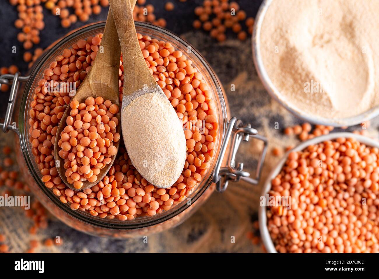 Red lentil and lentil flour in the wooden spoons over bowl of red ...