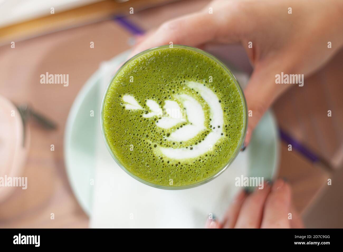 Top view glass of hot matcha green tea latte with art foam holding by woman hand on table Stock ...