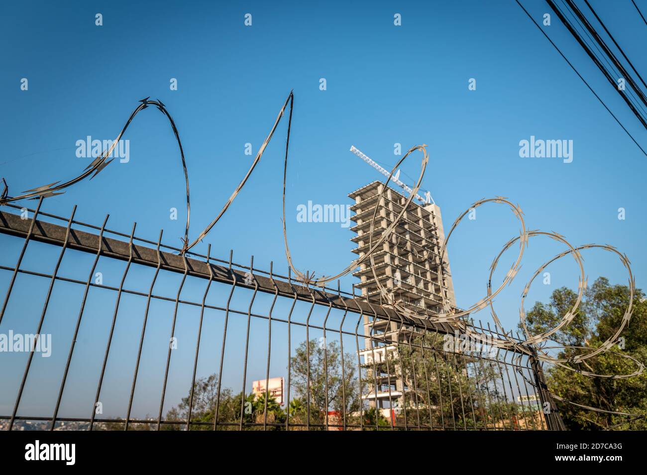 New construction high-rise with crane behind barbed wire fence Stock ...