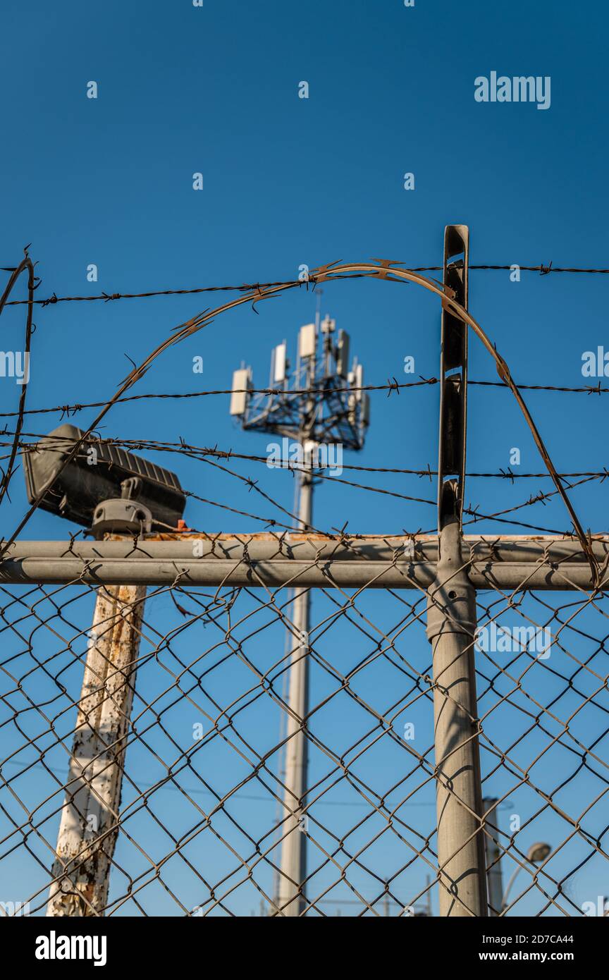 Barbed wire fence with cellphone communication tower behind it Stock ...