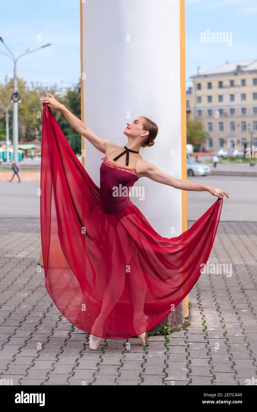 Woman ballerina in red ballet dress dancing in pointe shoes next to the ...