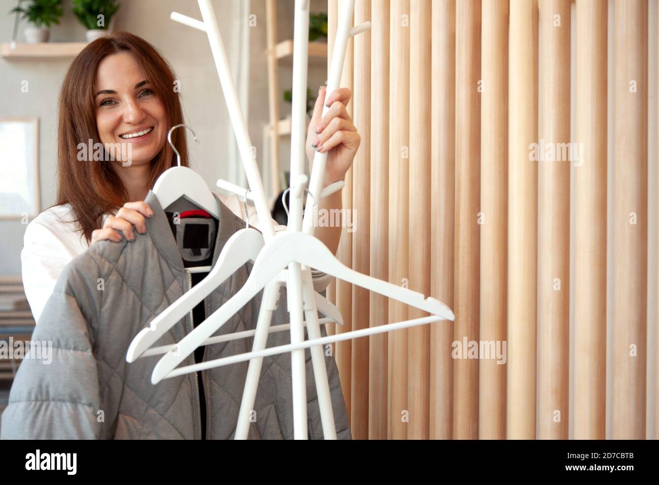 Beautiful young woman hanging empty white hanger on white stylish ...