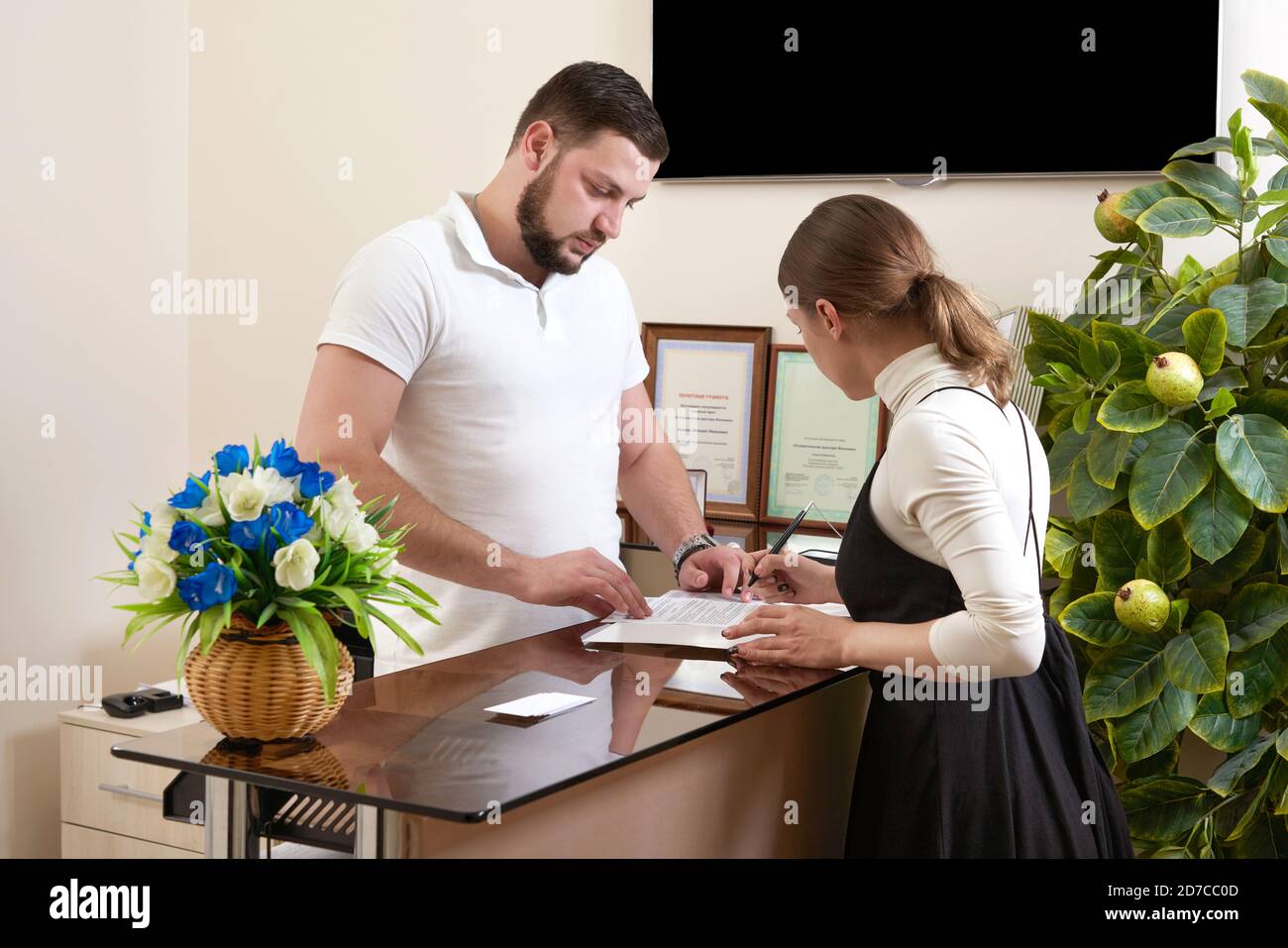 Man welcoming young woman client at office reception desk Stock Photo ...
