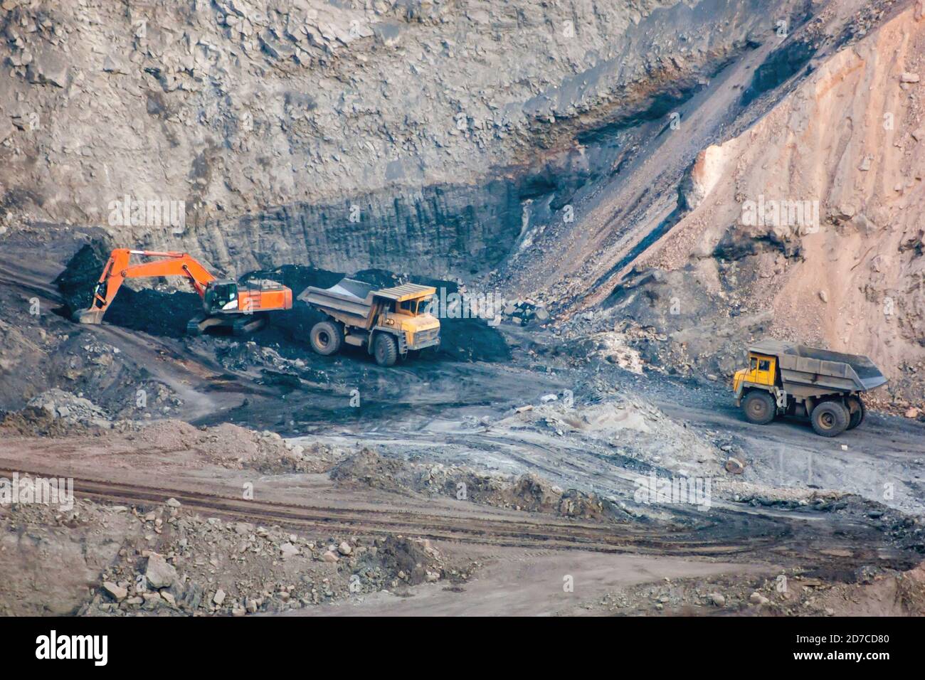 Crawler excavator and dump trucks are working in a quarry Stock Photo ...