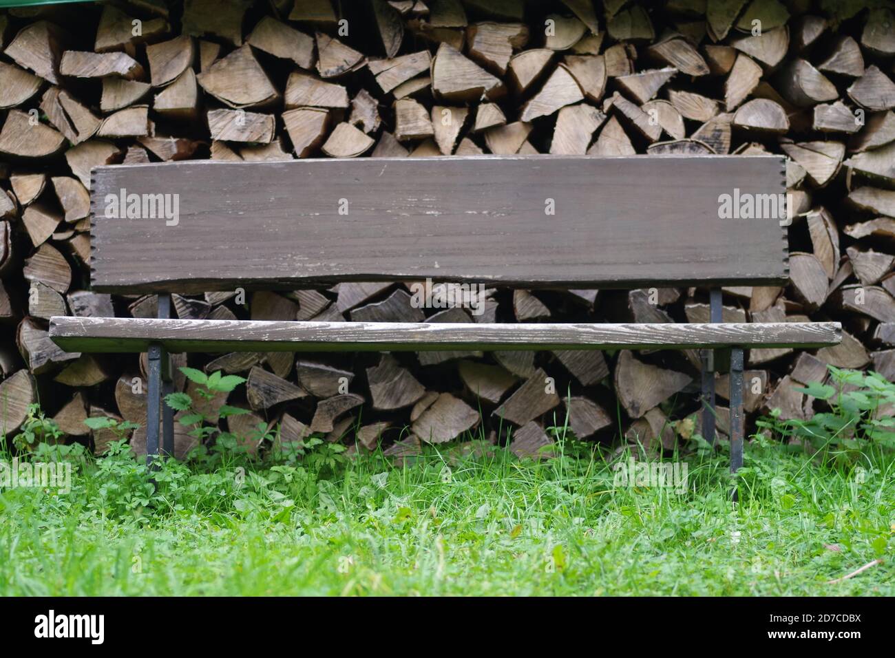 Old wooden bench on a background of a stack of logs Stock Photo - Alamy