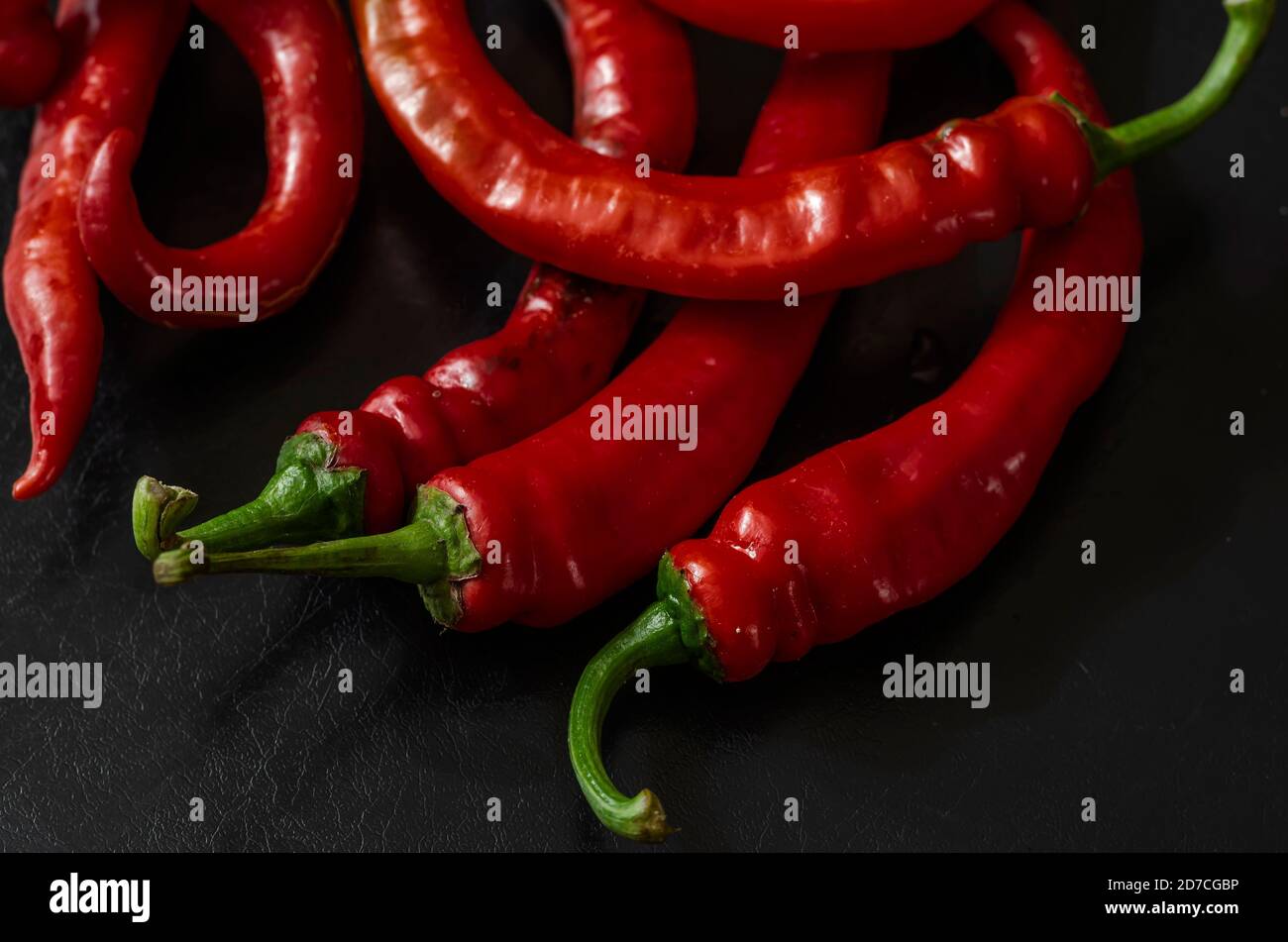 Pods of red hot chili peppers on a black background. Freshly plucked ...