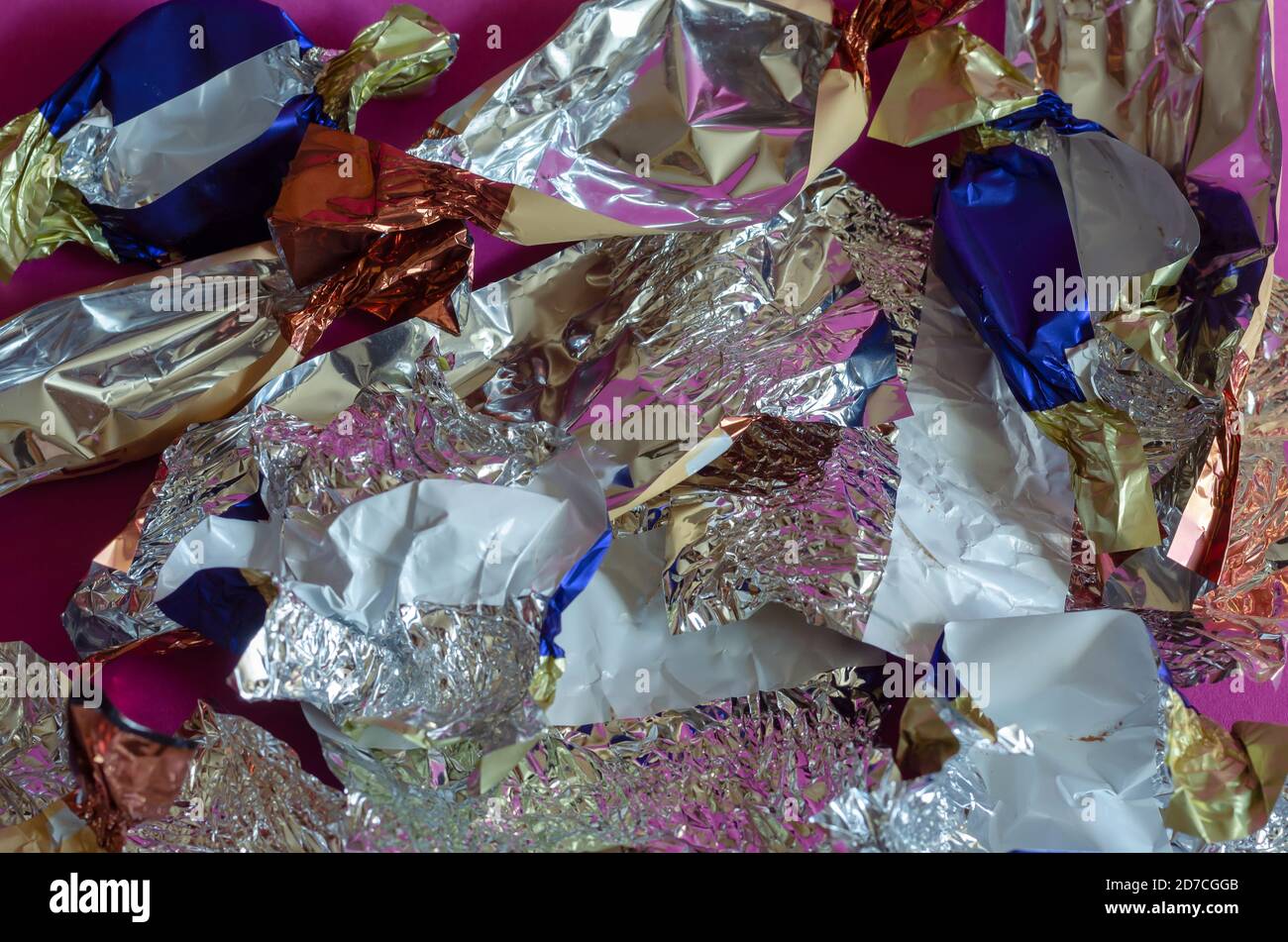 Lots of crumpled shiny candy wrappers on pink background. Empty ...