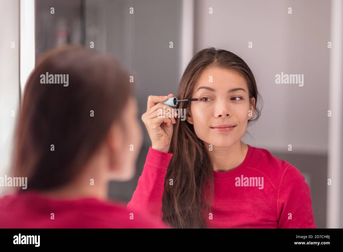 Woman putting make-up in the LED lighted mirror getting ready morning ...