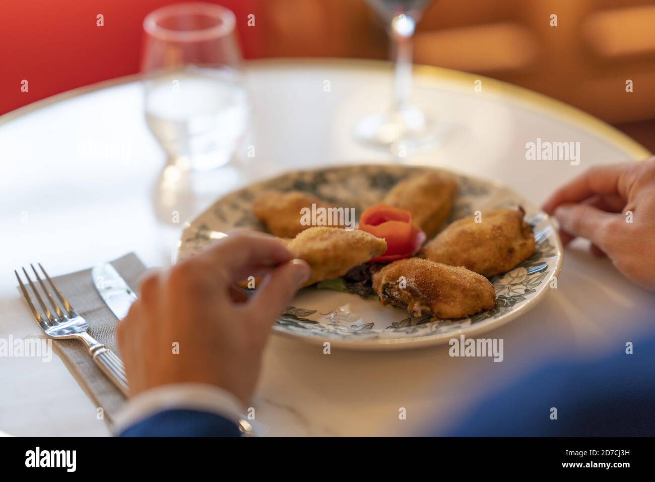 Closeup of a man eating crispy fried chicken fillets in a restaurant ...