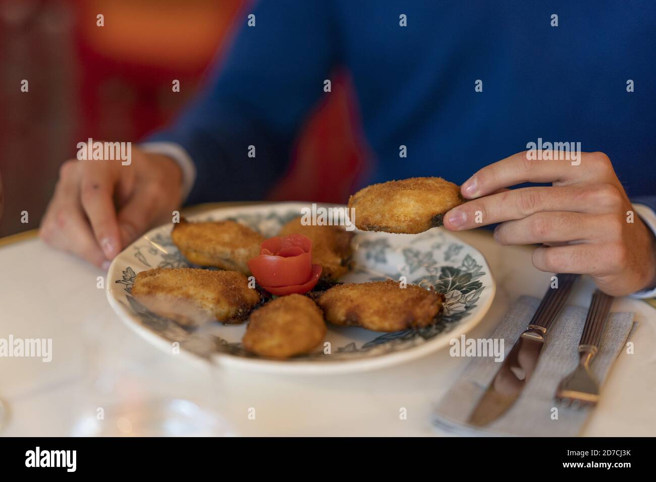 Closeup of a man eating crispy fried chicken fillets in a restaurant ...