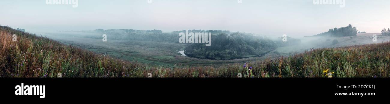 Beautiful summer cold hazy landscape with foggy hollow and green hills ...