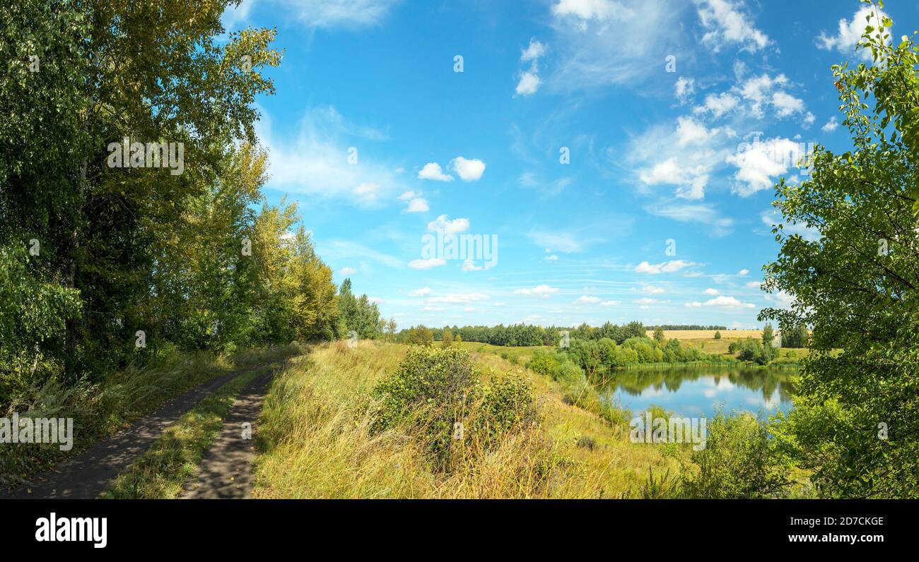 Sunny summer rural landscape with calm river,country road and golden ...