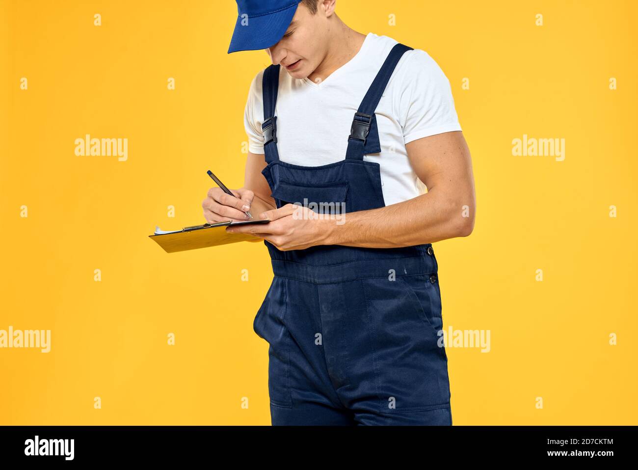 Man in working uniform documents rendering of services delivery service yellow background Stock ...